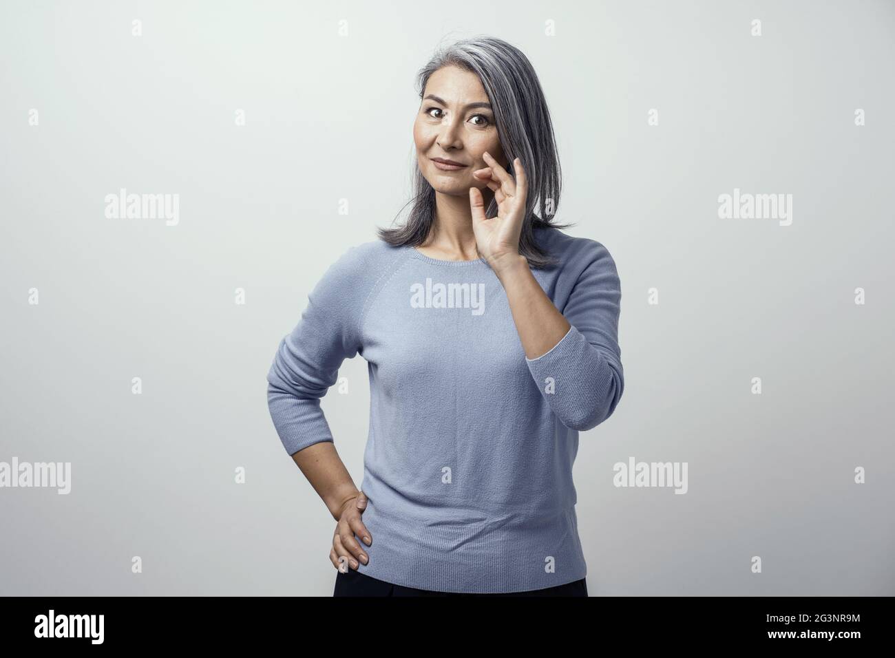 Smiling Asian woman touches her grey hair Stock Photo - Alamy
