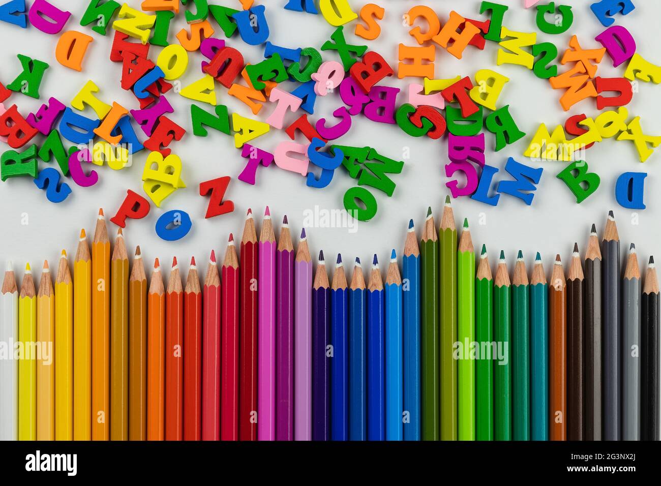 colored wooden pencils and letters of the english alphabet on a white ...