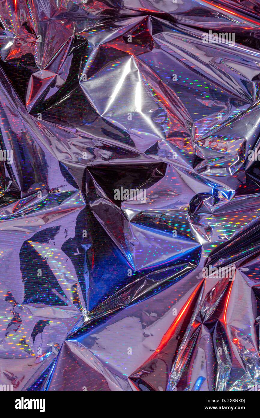The background of crumpled holographic packaging film with an abstract ...