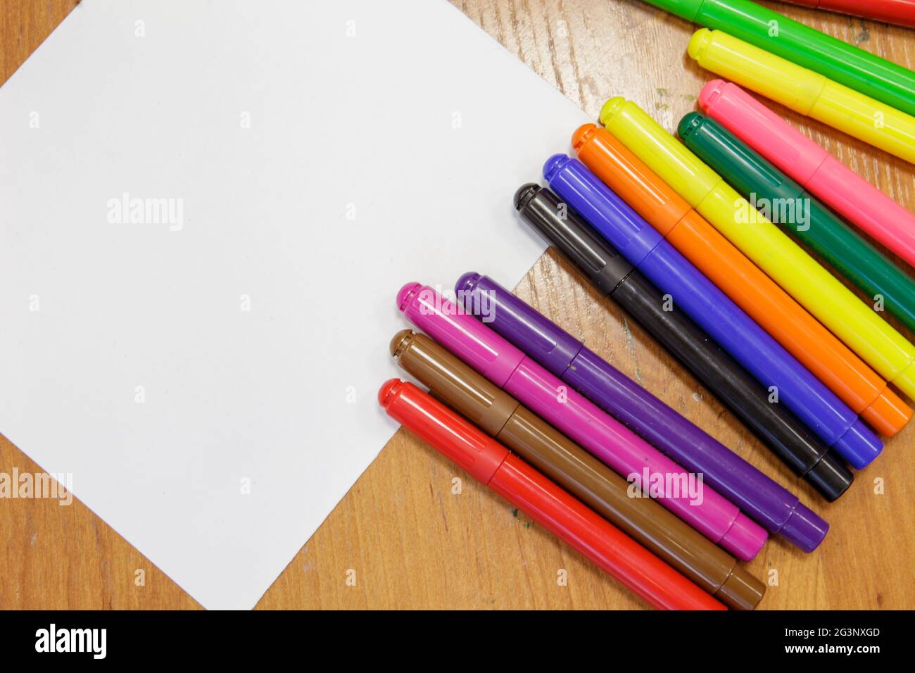 A set of colored markers and a sheet of white paper on the table Stock ...