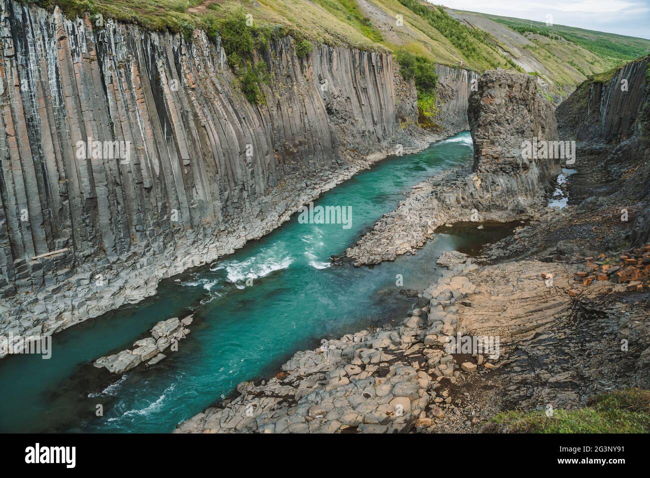 Studlagil basalt canyon, with rare volcanic basalt column formations and blue river from glacier ...
