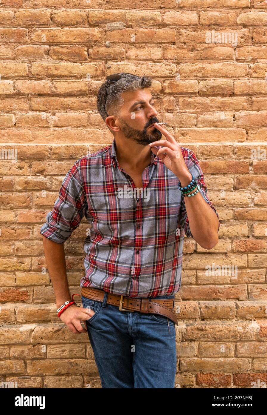 Male smoking a cigar against brick wall Stock Photo - Alamy