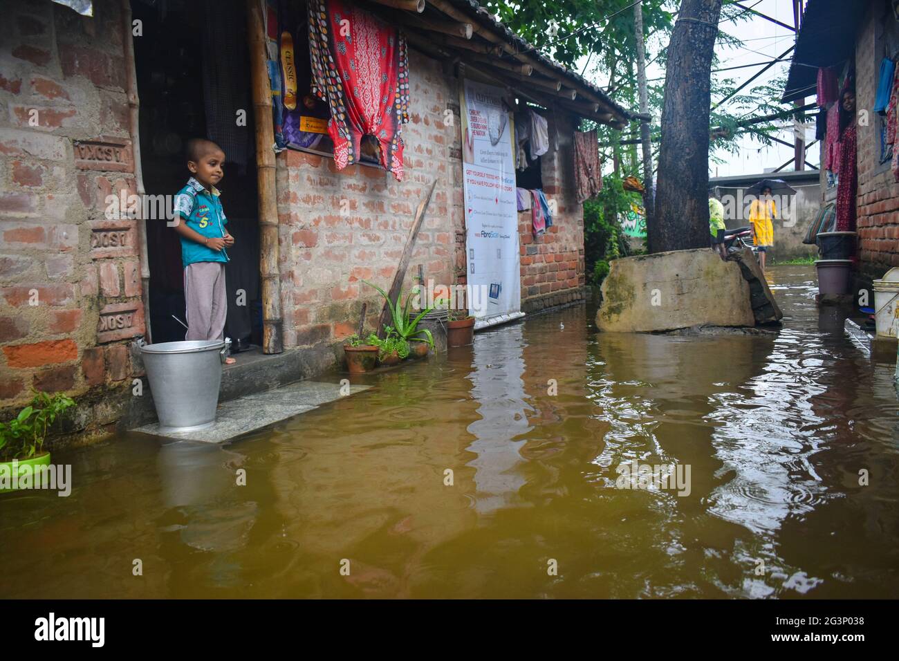 A little boy standing in front of his house which is flooded due to ...