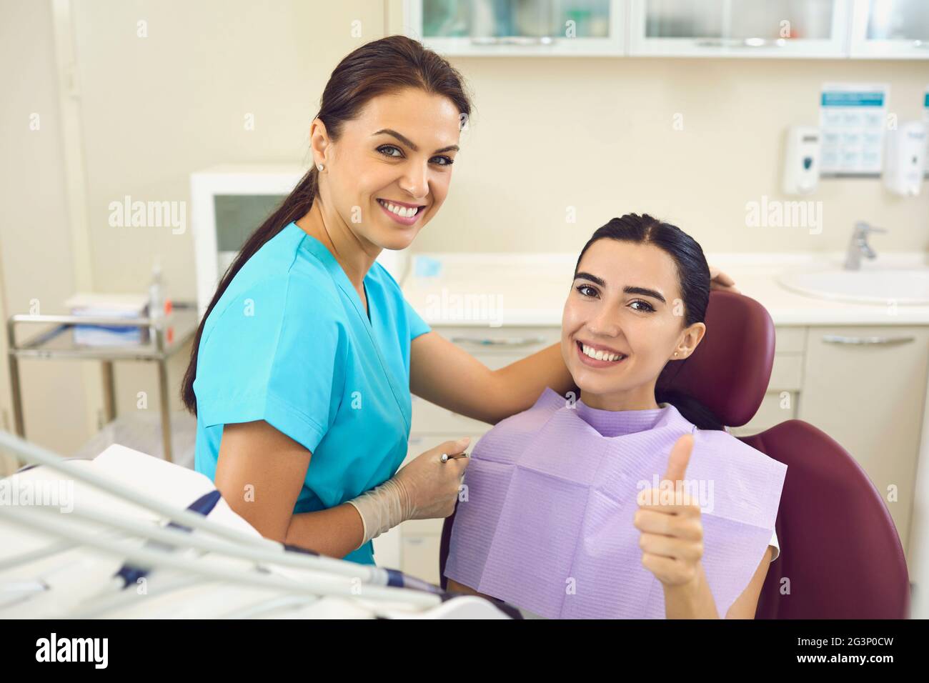 Happy patient in dental chair giving thumbs up and smiling with ...