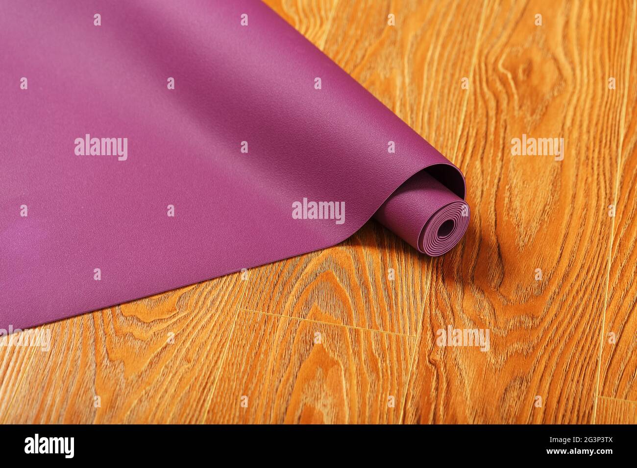 An unfolded lilac-colored yoga mat is unfolded on the wooden floor. Top ...
