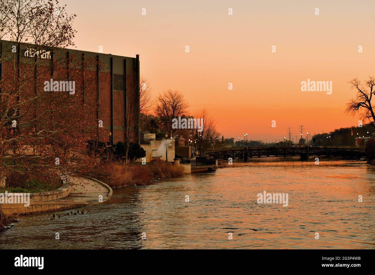 Elgin, Illinois, USA. Light comes on along streets and bridges spanning ...