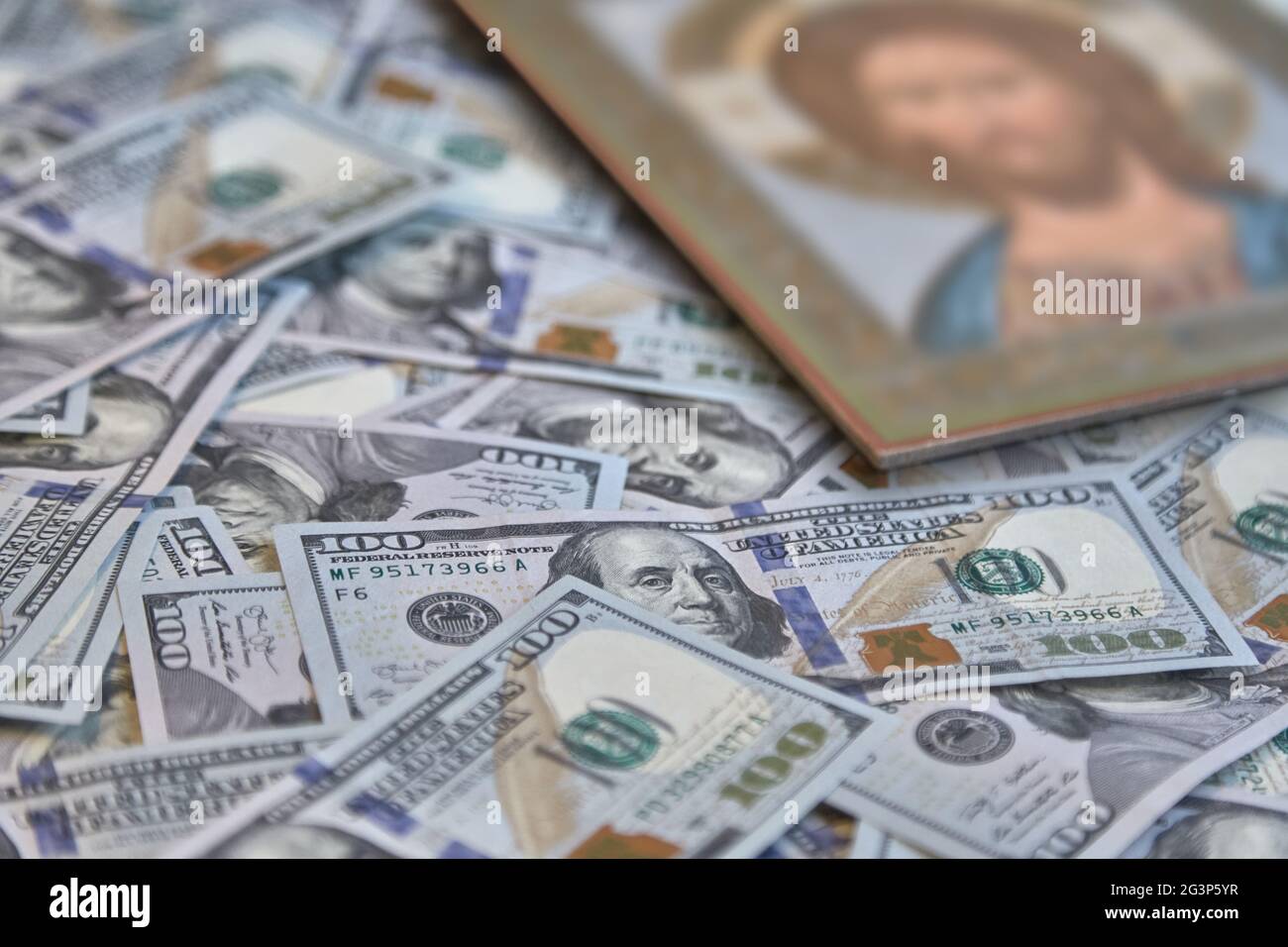 silhouette of a religious icon against a background of hundred-dollar ...