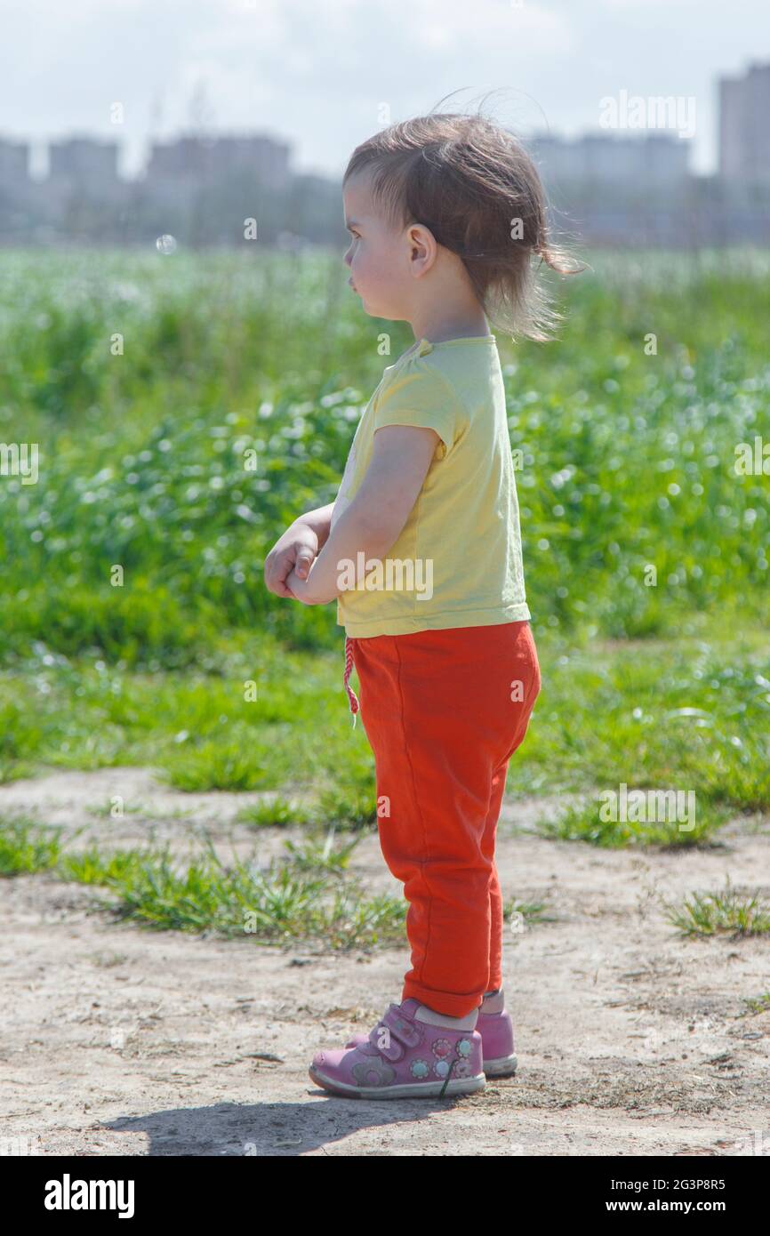 A small child standing at full height on the grass Stock Photo - Alamy