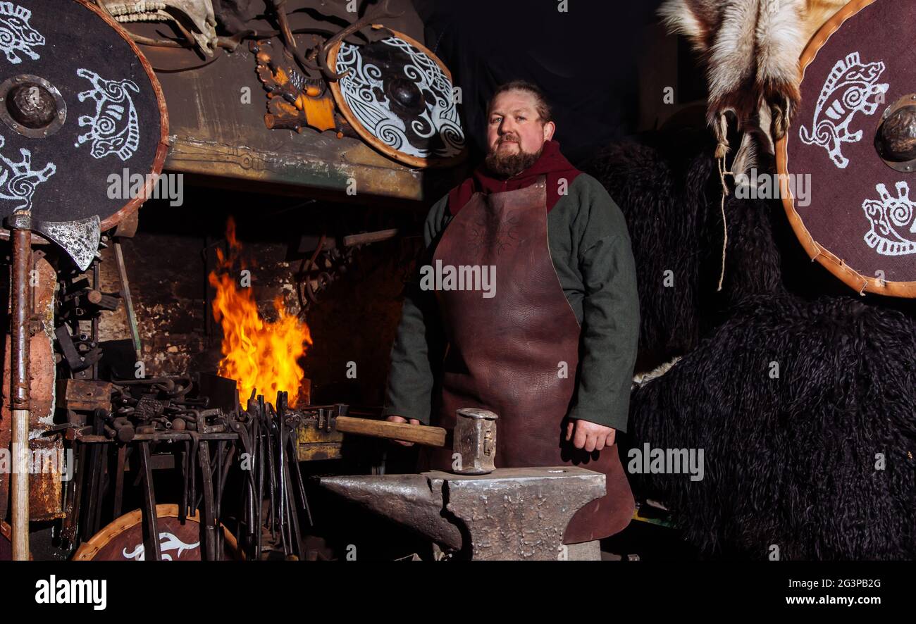 Viking forges weapons and swords in the smithy. A man in a warrior's ...