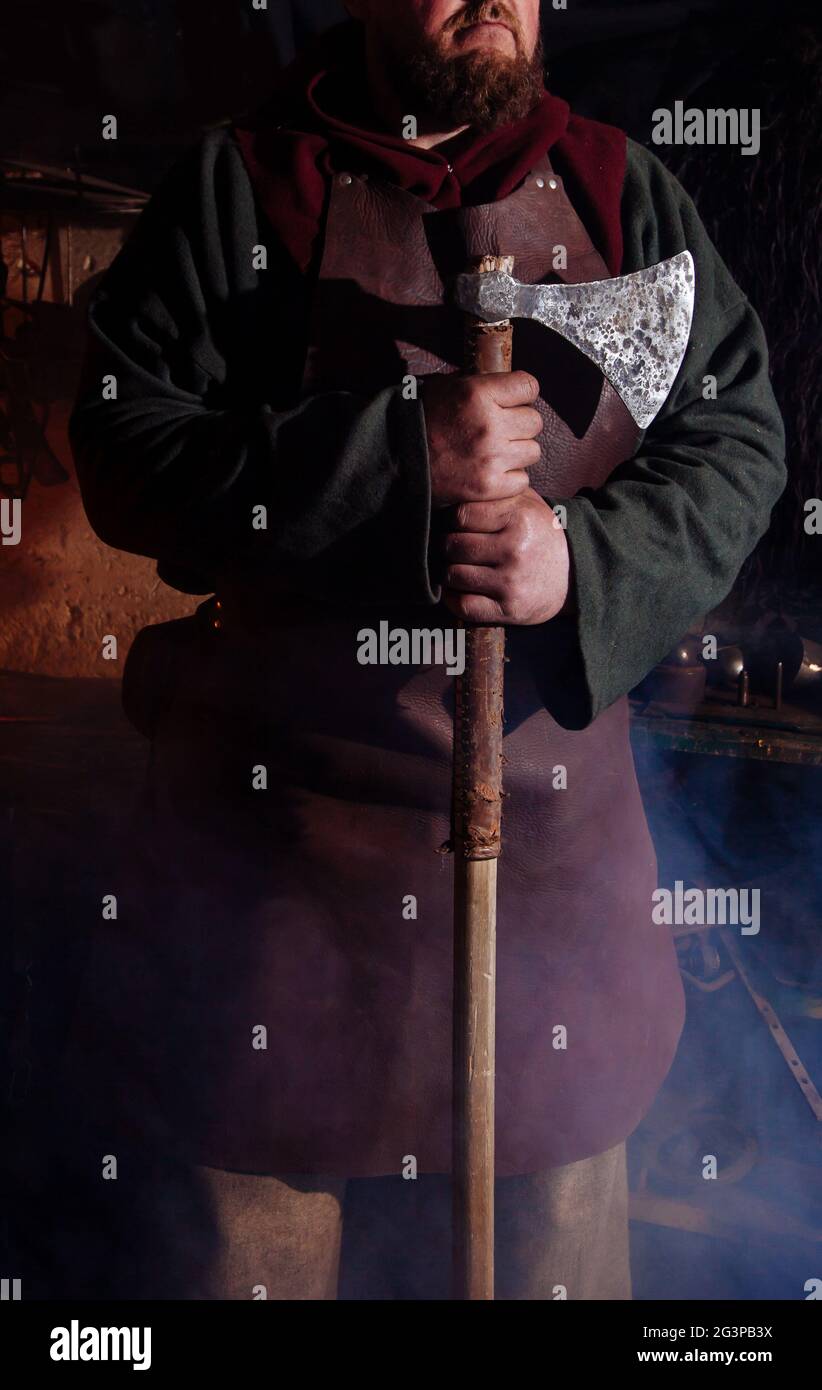 Viking forges weapons and swords in the smithy. A man in a warrior's ...