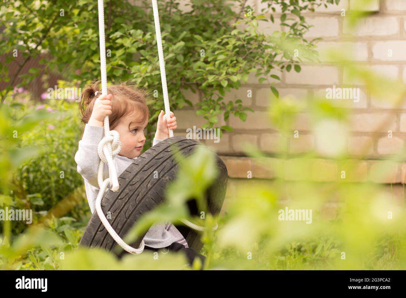 Little red-haired girl riding a wheel outdoors Stock Photo - Alamy
