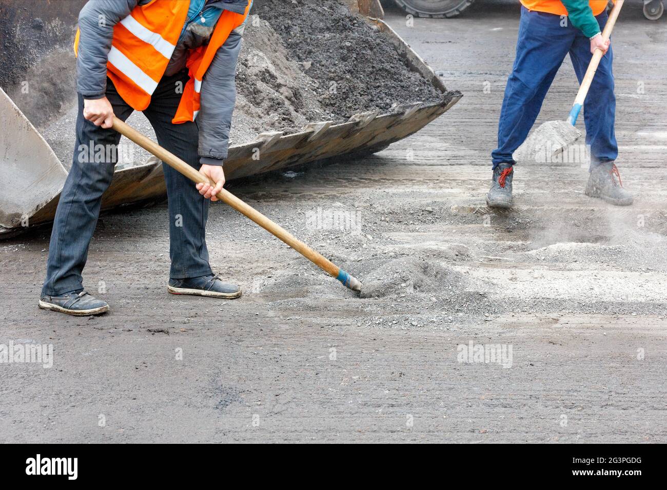 Road workers in bright orange reflective vests are repairing old road ...
