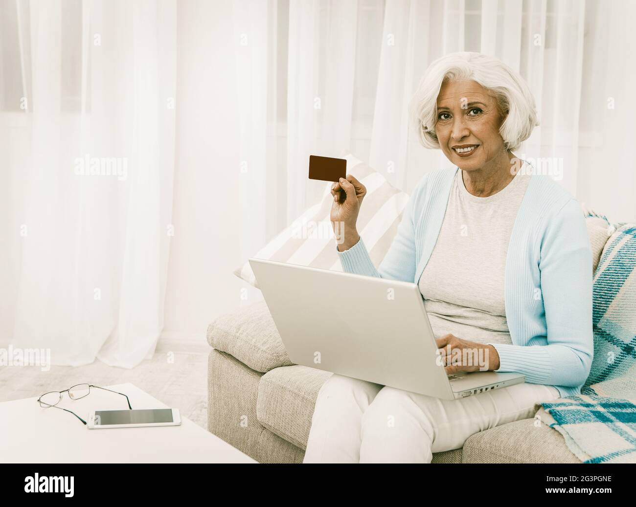 Pretty Senior Lady Holding A Credit Card To Pay Bills Via The Internet ...