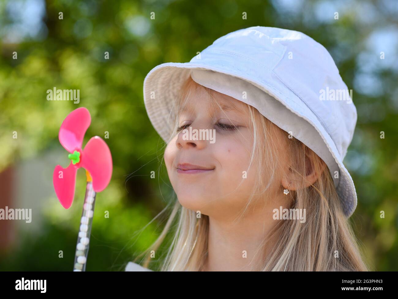 Little girl blowing on a fan in summer Stock Photo - Alamy