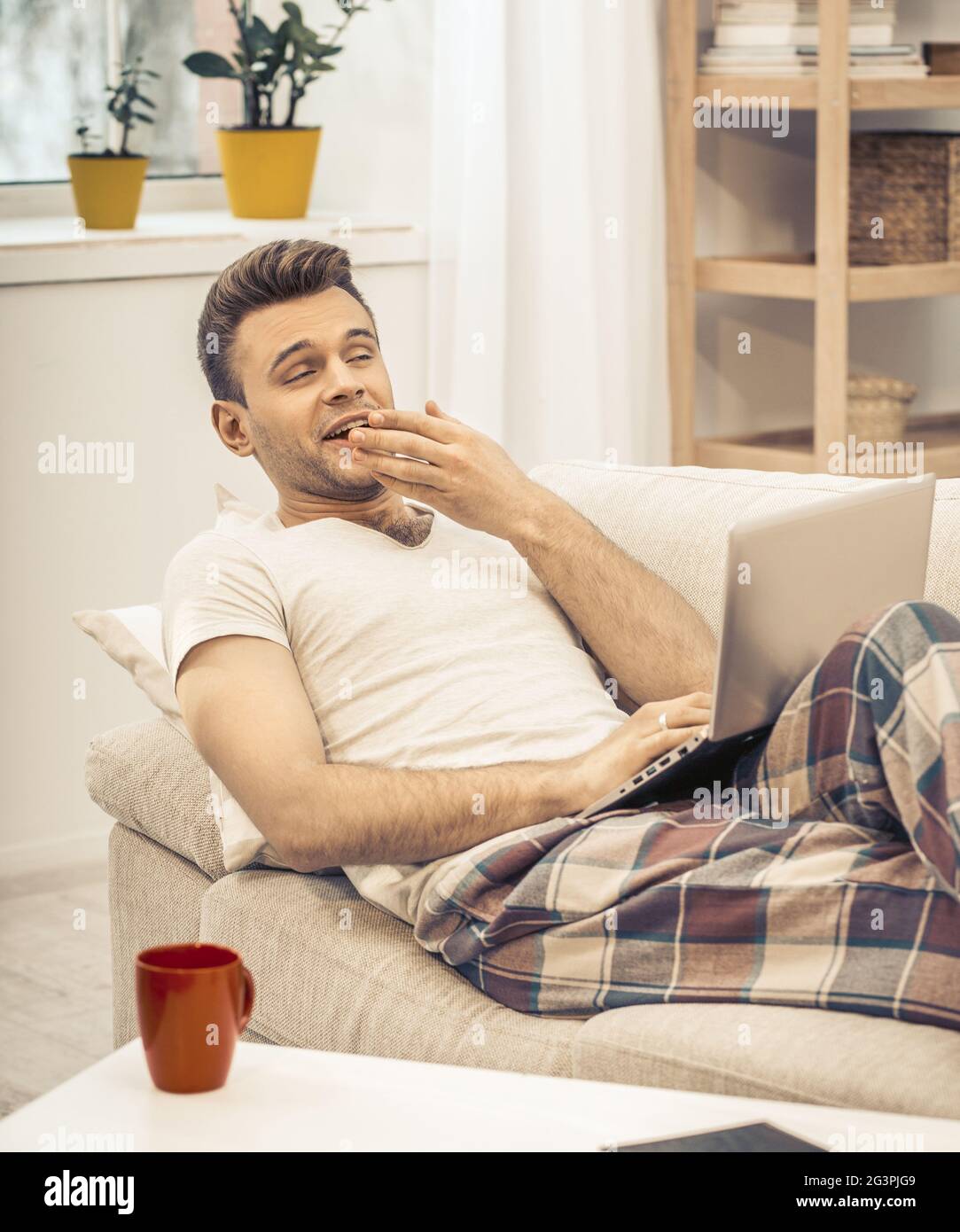 Bored man in Casual lying on sofa and yawning Stock Photo - Alamy