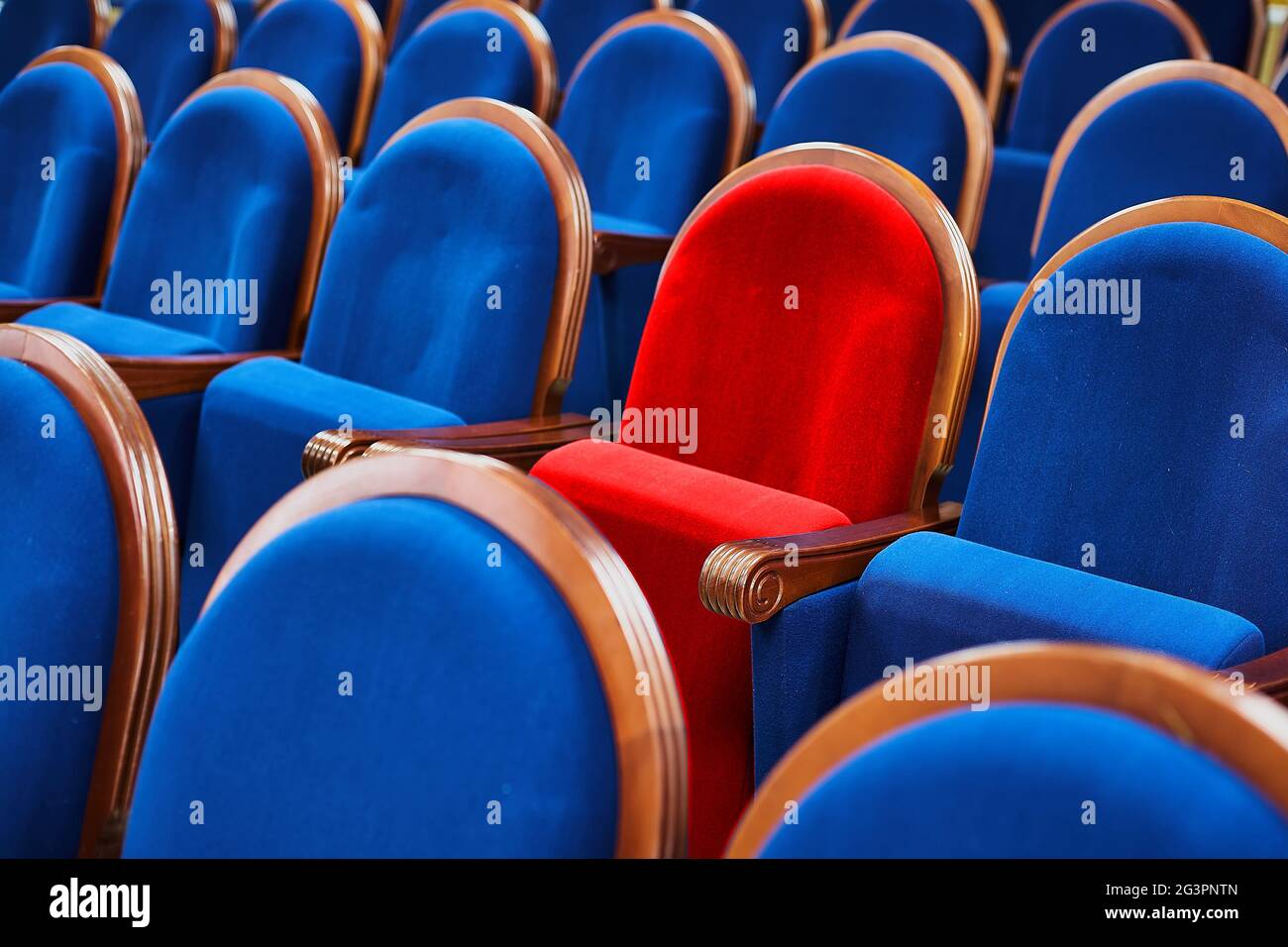 Red chair among the blue seats. Special or VIP seat in the meeting room ...
