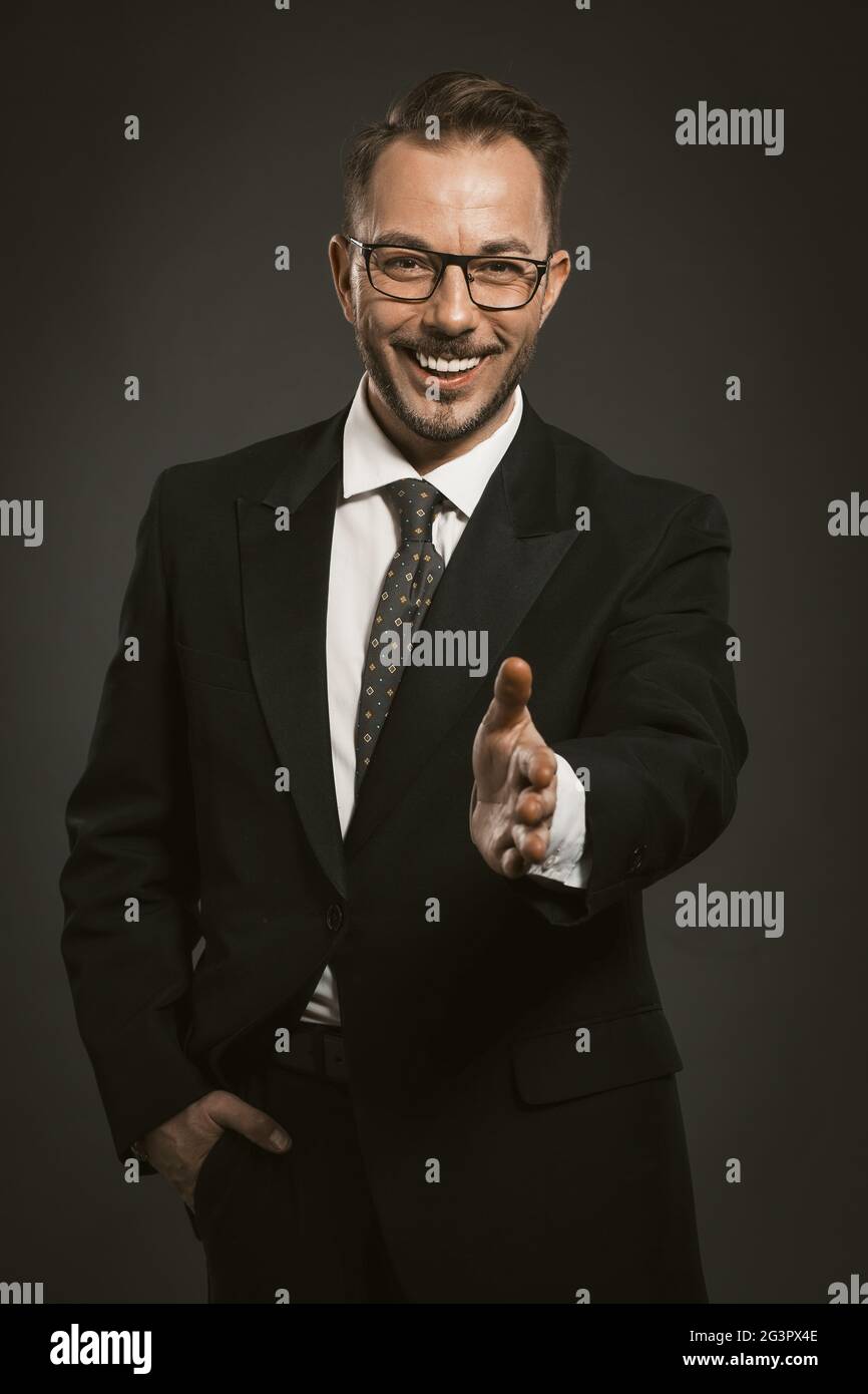 Handsome entrepreneur giving hand to handshake. Friendly businessman ...