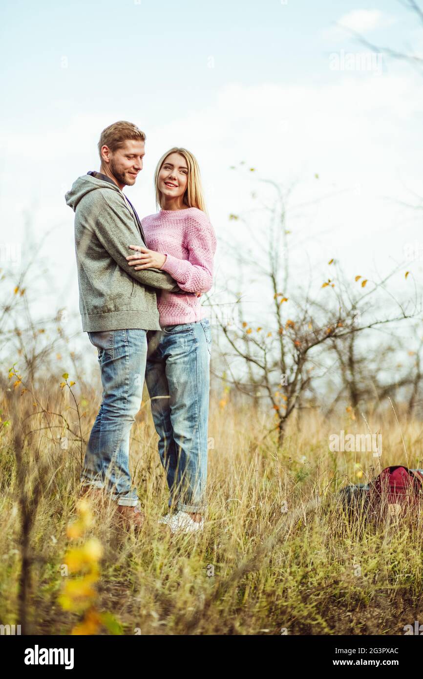 Hugs in nature. Young woman and man stands hugging in the field against ...