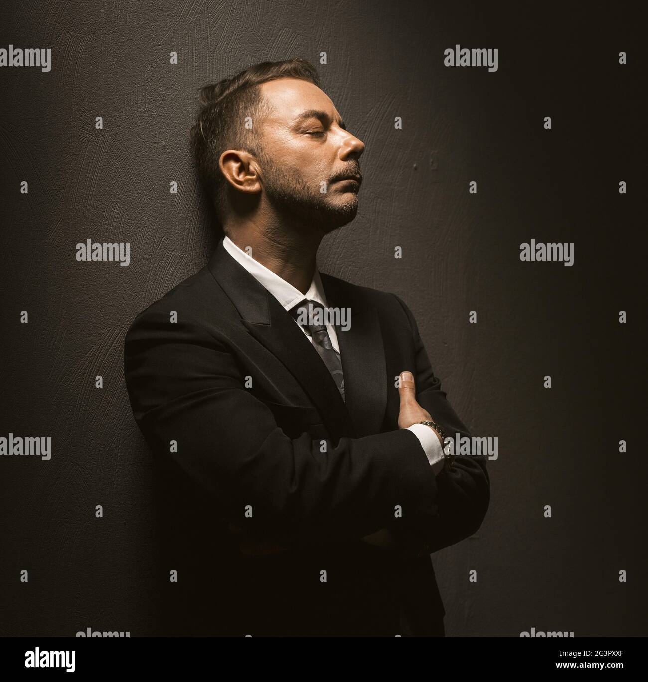 Depressed businessman stands in dark room. Sad man stands with his eyes ...