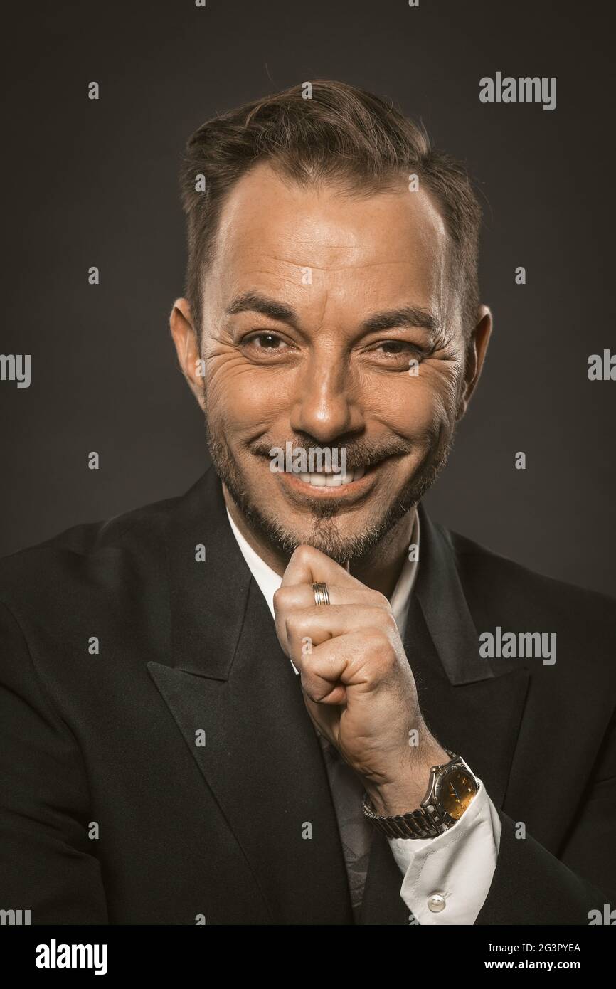 Attractive businessman charmingly smiling while looking at the camera ...