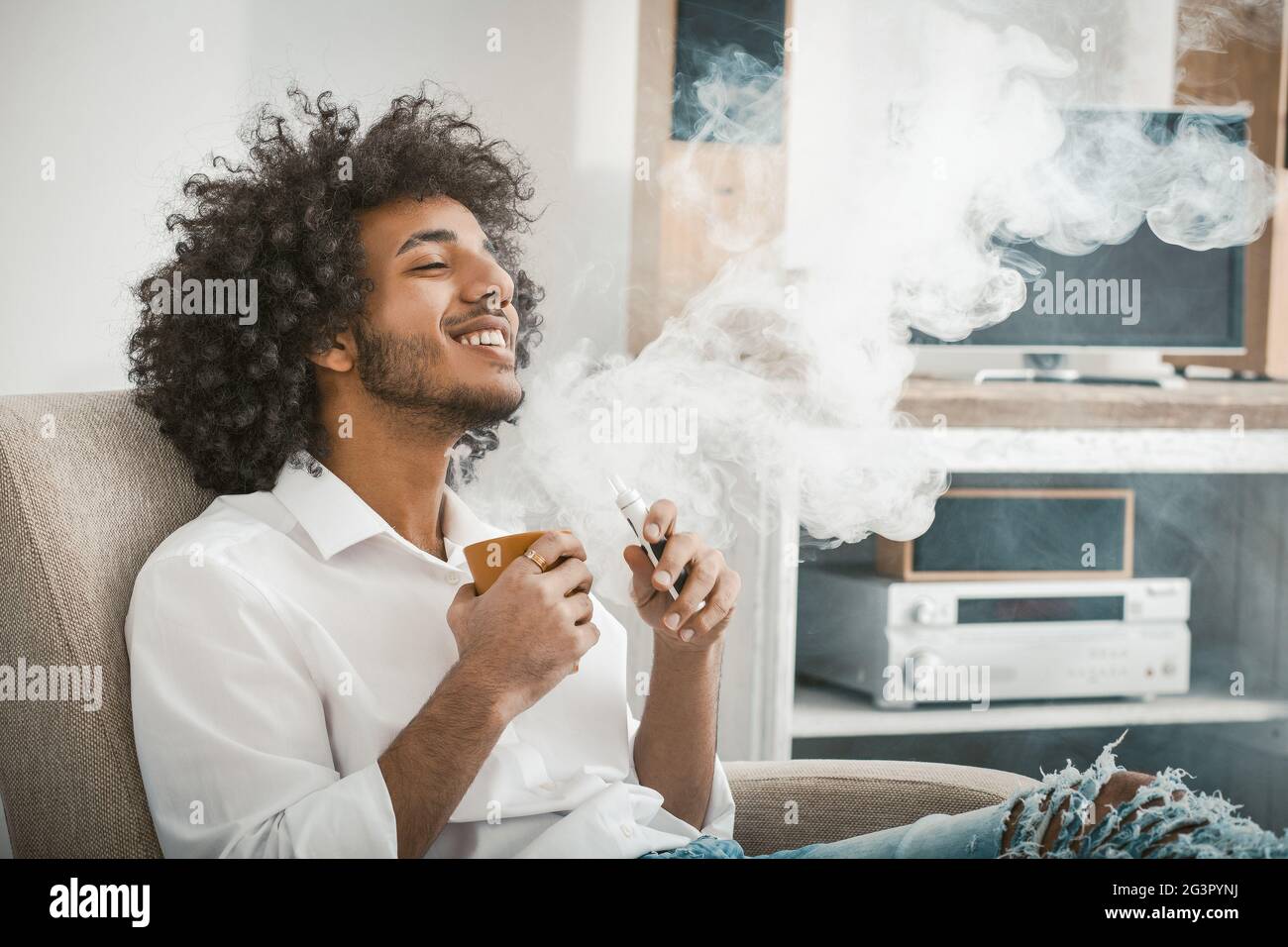Handsome man enjoys relaxing holding cup of drink in his hands. Young ...