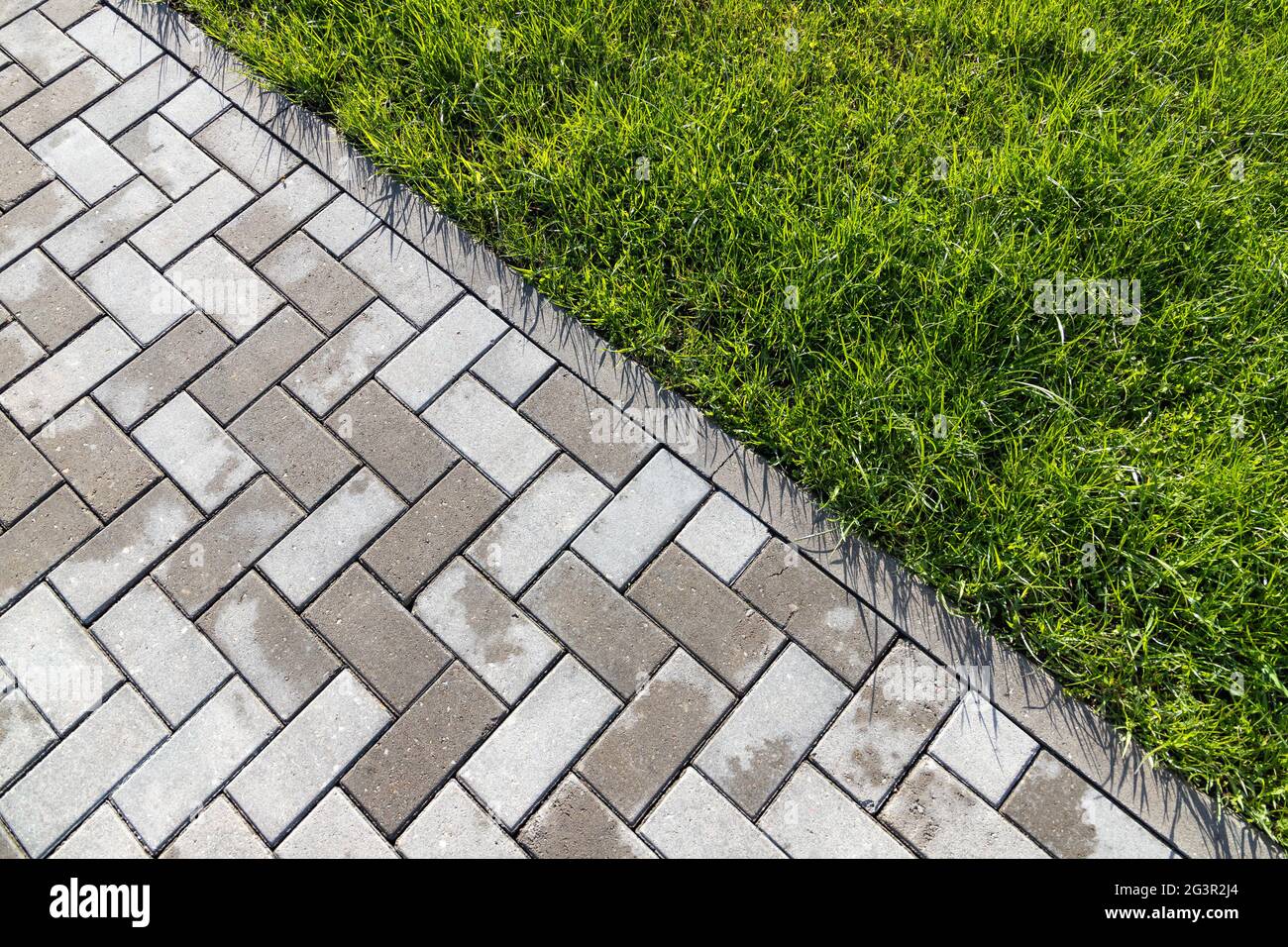 Cobbled road and green grass. Concrete street pavement, top view ...