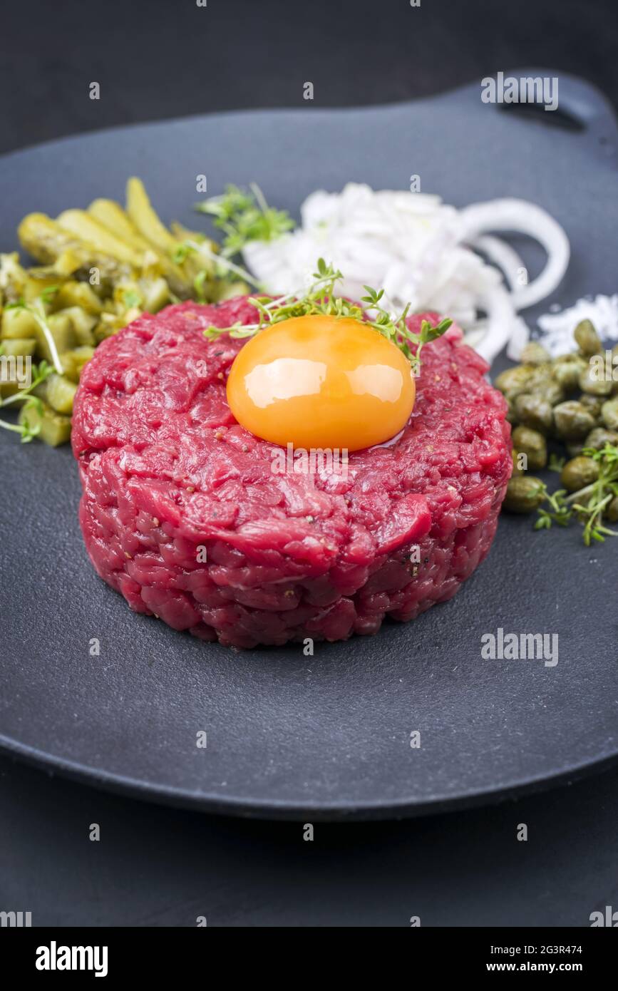 Gourmet tartar raw from beef fillet with yellow of the egg and gherkin ...