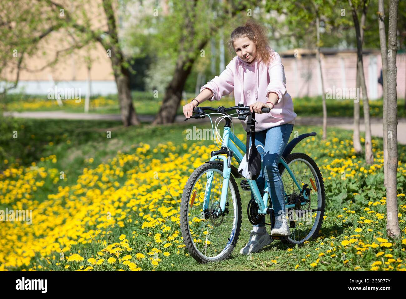 Teenager Caucasian girl standing with her blue bicycle on pathway with ...