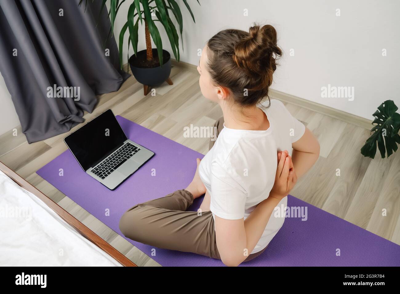 Healthy young female meditating at home watching online tv yoga class e ...