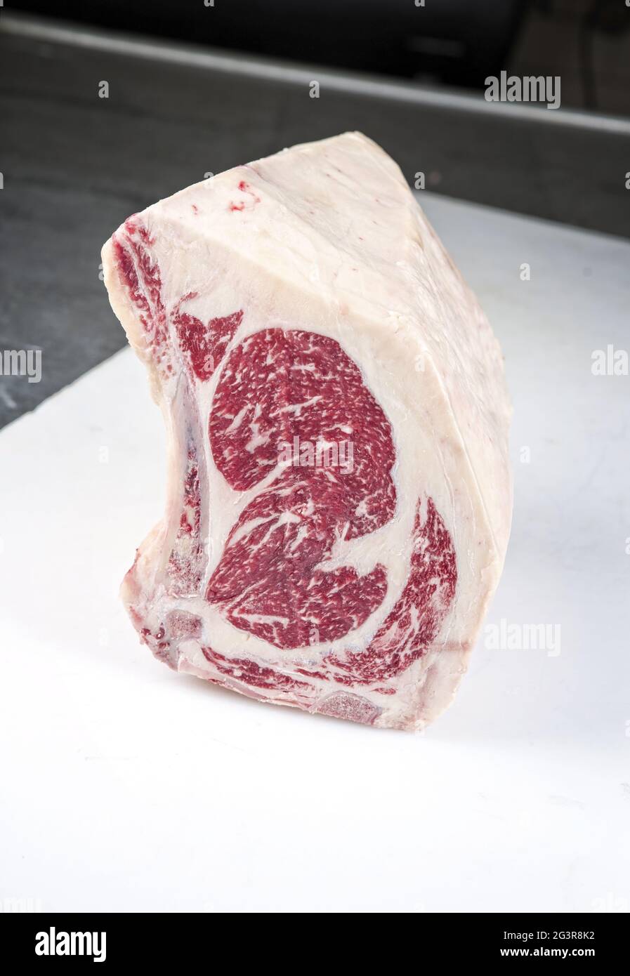 Raw dry aged wagyu cote de boeuf beef block as closeup on white board ...