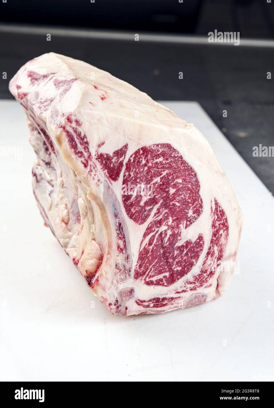 Raw dry aged wagyu cote de boeuf beef block as closeup on white board ...