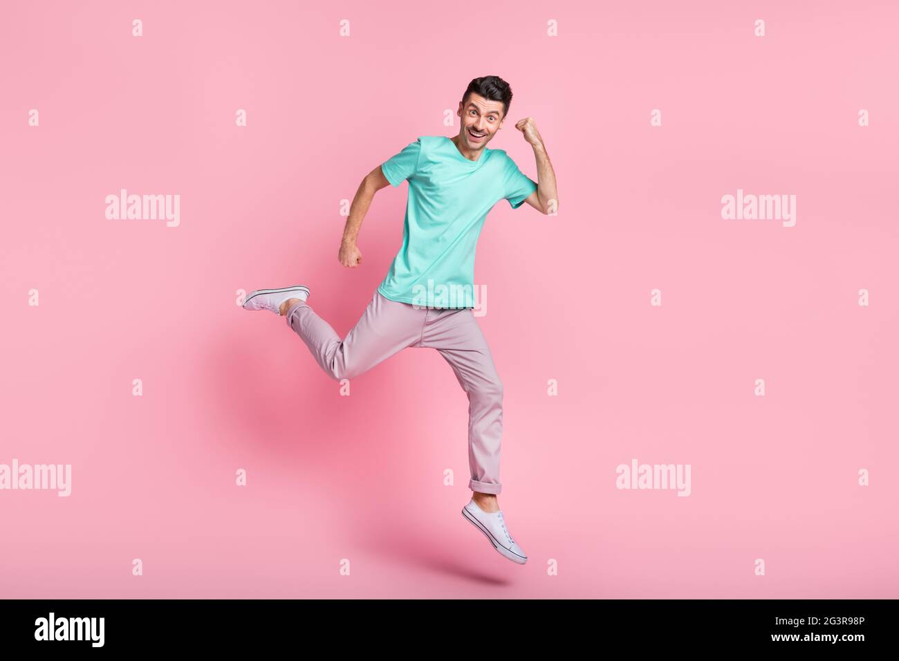 Full body photo of young excited man go run jump rejoice victory fists ...