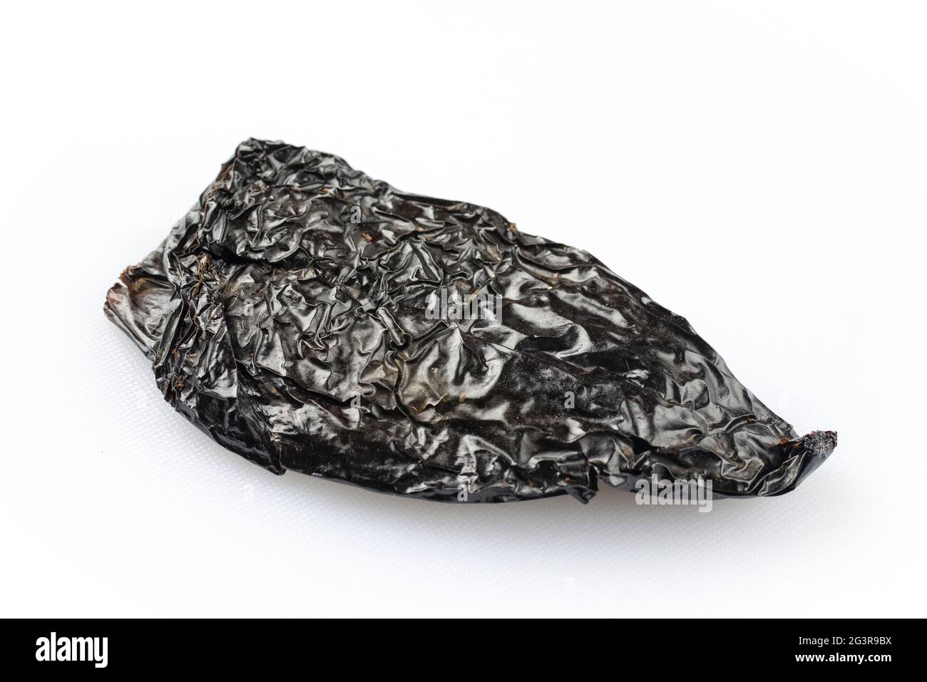 Dried Mexican black hot ancho chili offered as close-up on white ...