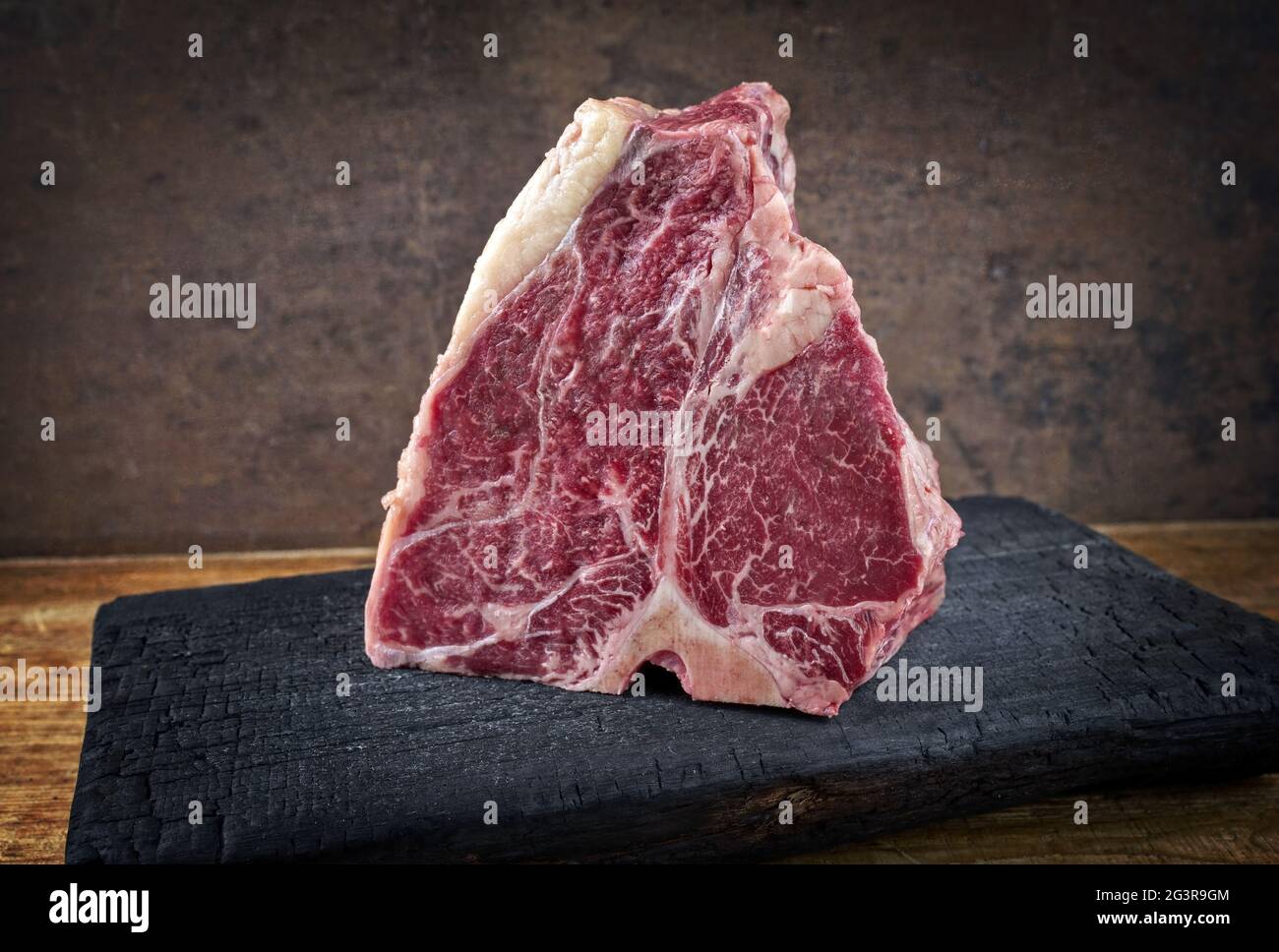 Raw dry aged wagyu porterhouse beef block offered as close-up on black ...