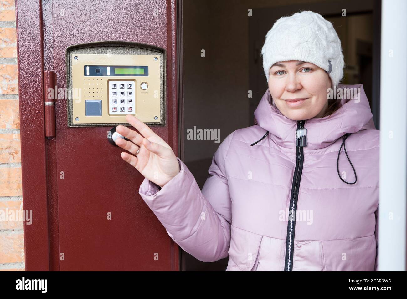 Attractive woman standing in doorframe with intercom, dwelling house ...
