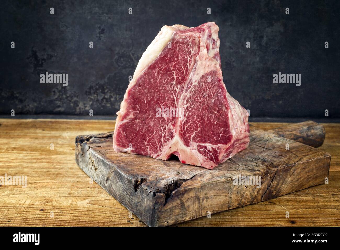 Raw dry aged wagyu porterhouse beef block offered as close-up on black ...