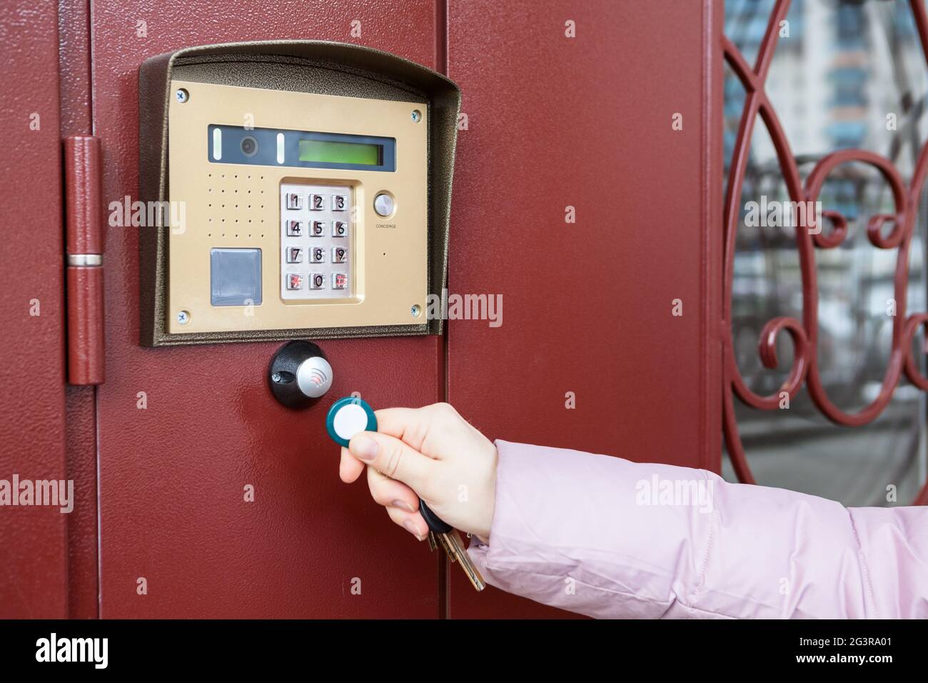 Person with wireless key touching intercom for house access, close up ...