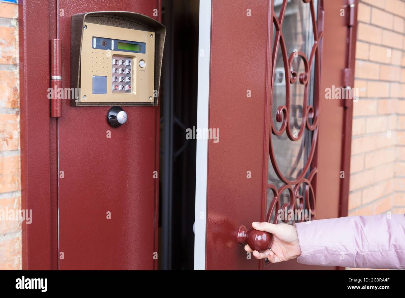 Caucasian female hand opening steel heavy door after intercom ...