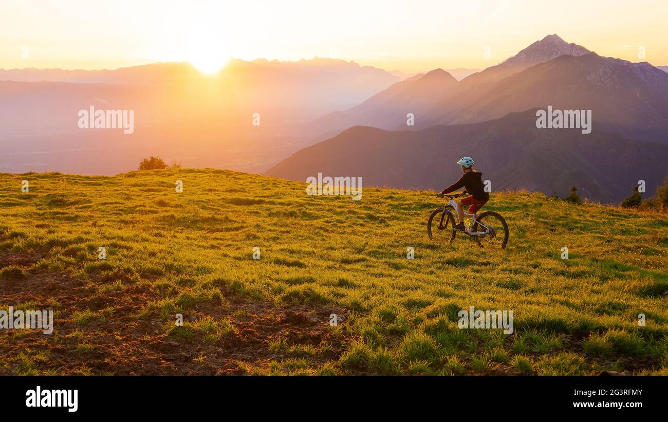 Girl child riding mountain bike into the sunset. Beautiful golden ...
