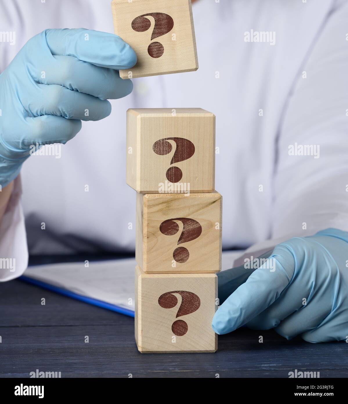 wooden cube with a question mark in the doctor's hand on a blue ...