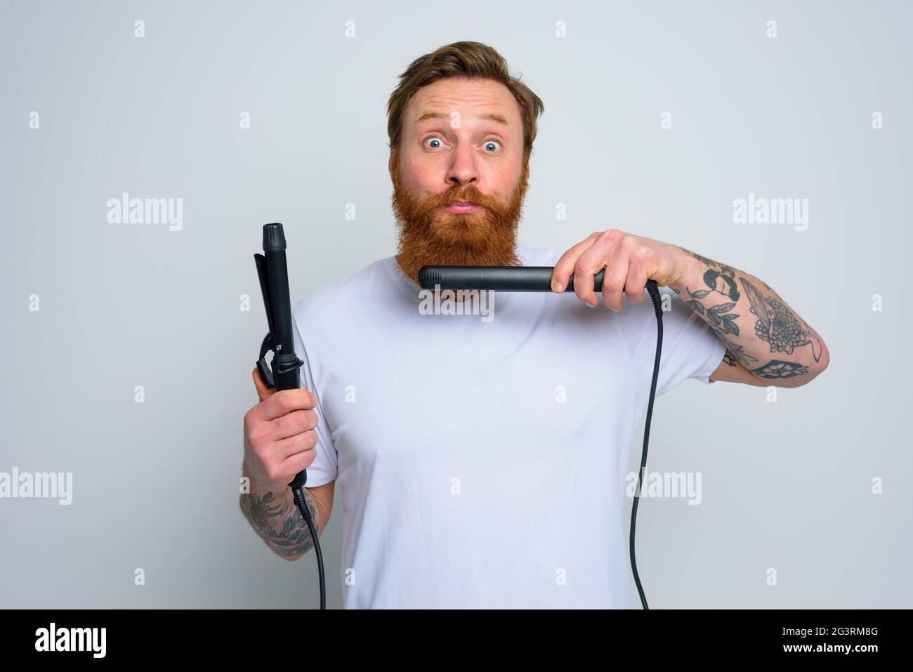 Undecided man hair with straightener is ready to work Stock Photo - Alamy