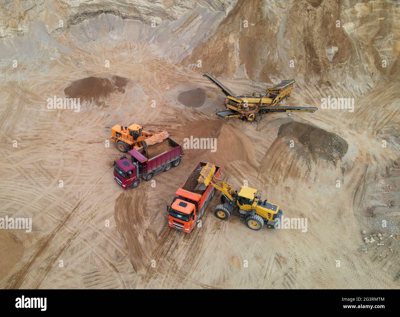 Wheel loader loading sand into dump truck in open pit. Arial view of ...