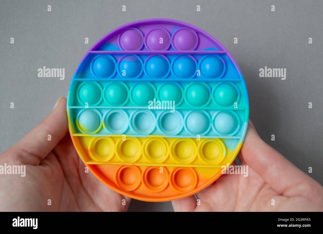 Bright colorful silicone Pop it toy. Popular anti-stress toy on a gray ...