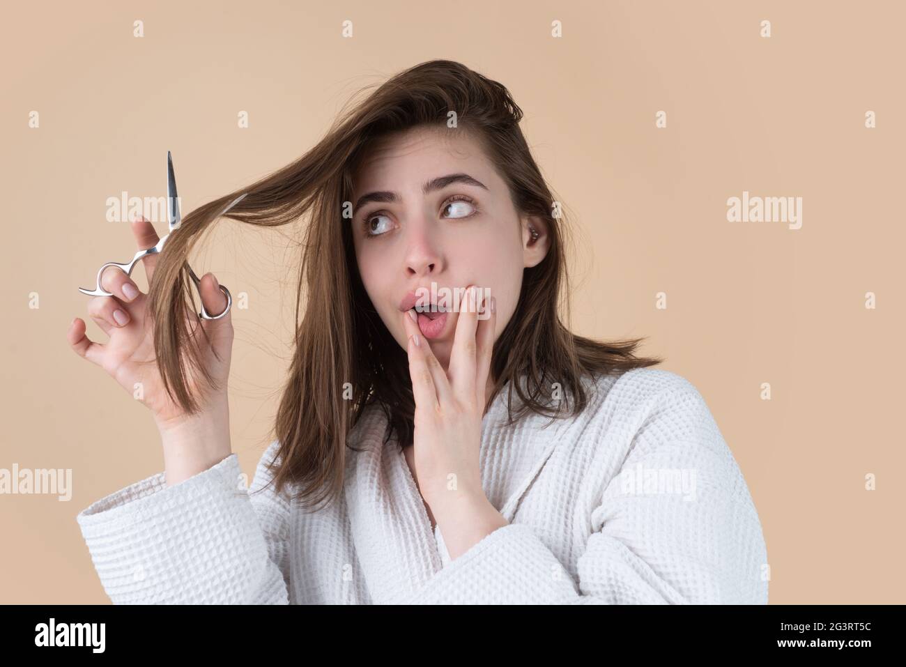 Sad woman having her hair cut with scissors. Beautiful woman in panic ...