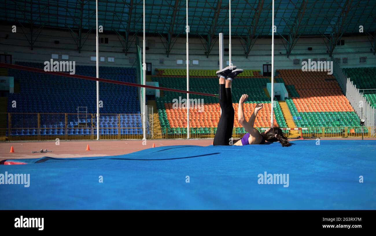 Sportswoman falling on mat after high jump Stock Photo - Alamy