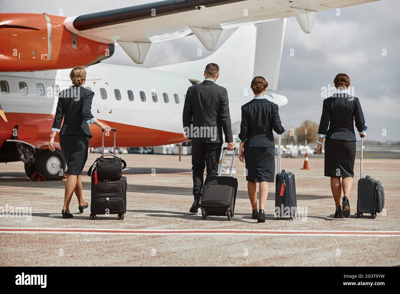 Plane team walking on runway to airplane Stock Photo - Alamy