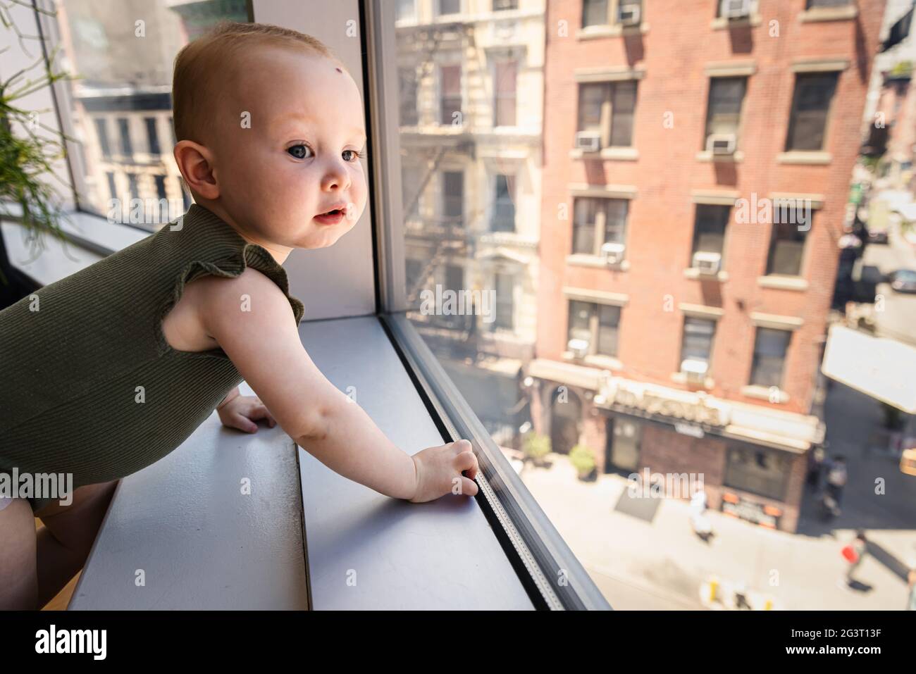 Curious happy baby girl looking out window in city Stock Photo - Alamy