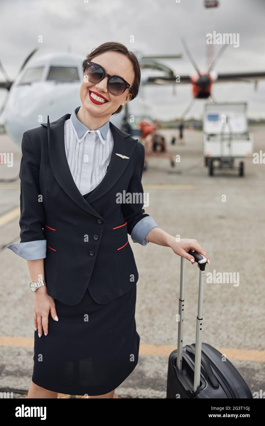 Stewardess with baggage on runway near airplane Stock Photo - Alamy