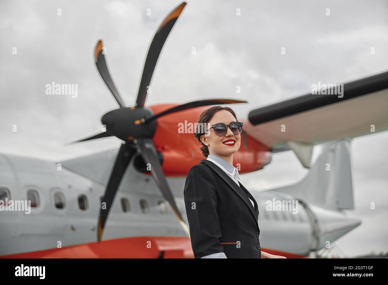 Young stewardess on background of airplane jet Stock Photo - Alamy