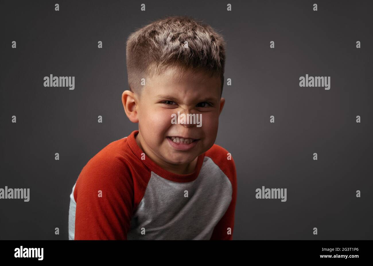 Adorable playful little kid seated on photo studio. isolated over grey ...
